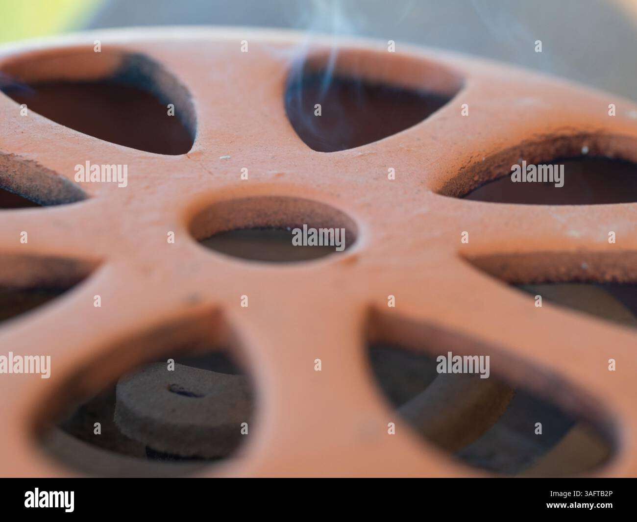 A wisp of smoke from a mosquito coil in a decorative Terracotta holder ...