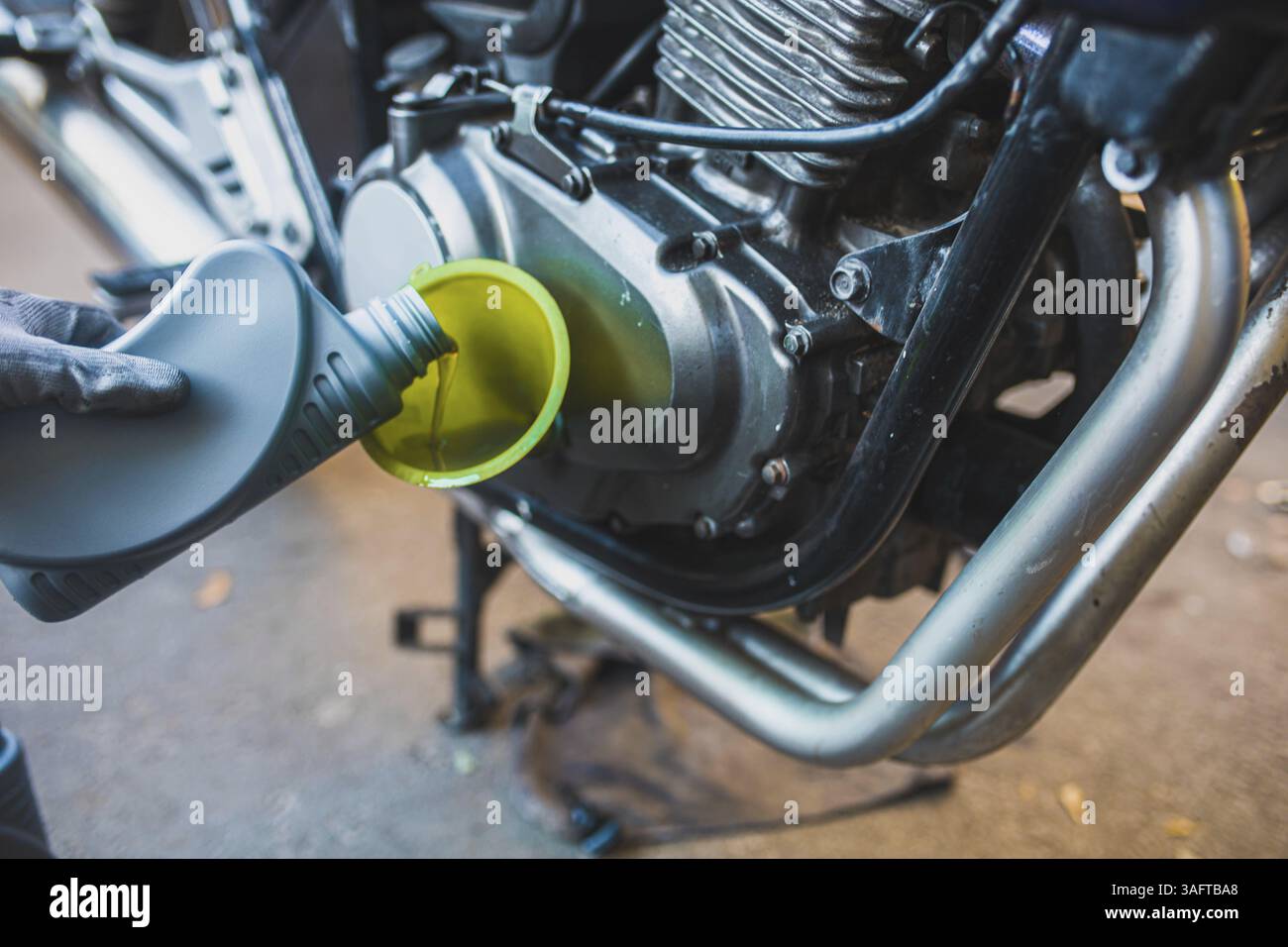 Detailed view of engine oil being poured through a funnel into a ...
