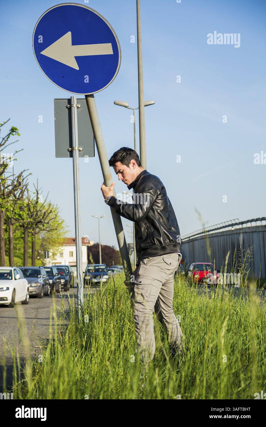 Young Man Wearing Leather Jacket Moving Arrow Road Sign in Long Green ...
