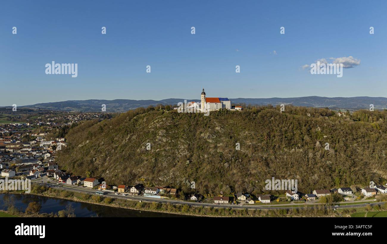 Impressive hill with church, surrounded by town and forest, under blue ...