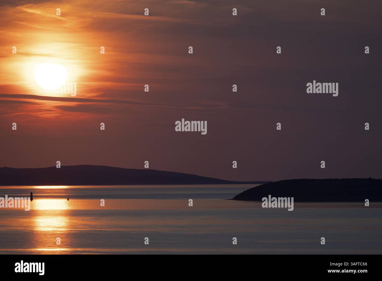 Sunset, sun sinks glowing red behind the islands of Anglesey and Puffin ...