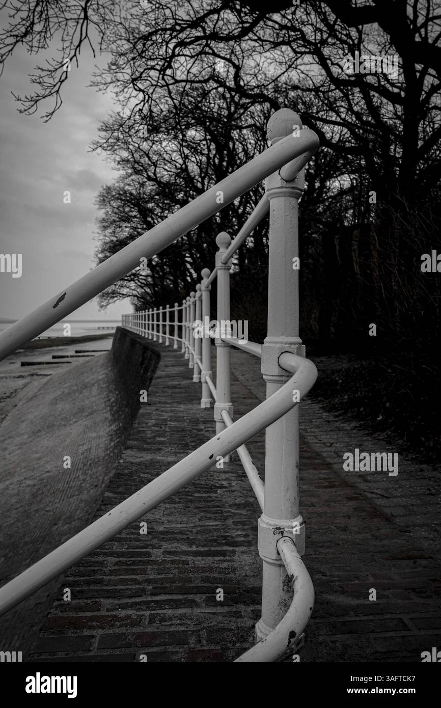 A railing along a cobbled path on the coast, black and white, North Sea ...