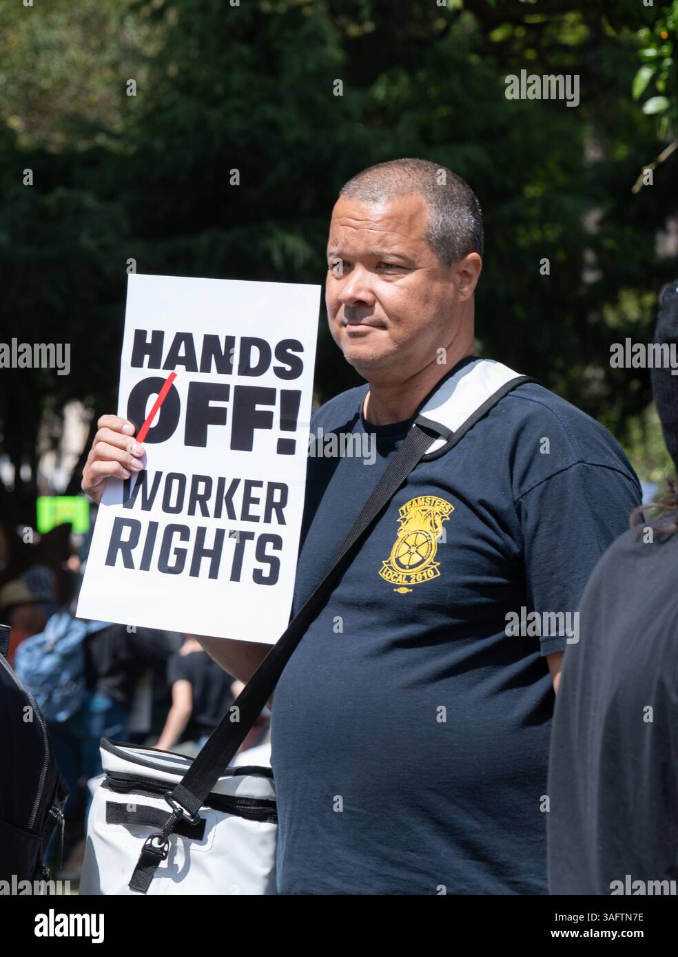 A Teamsters union member holds up a sign about hands-off worker rights ...