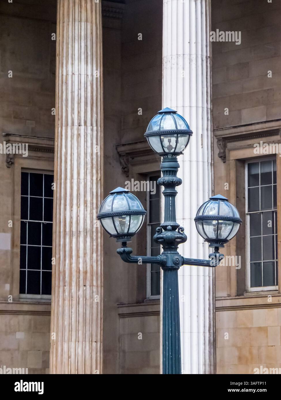 A three-head lamp post stands in front of two columns at a building in ...