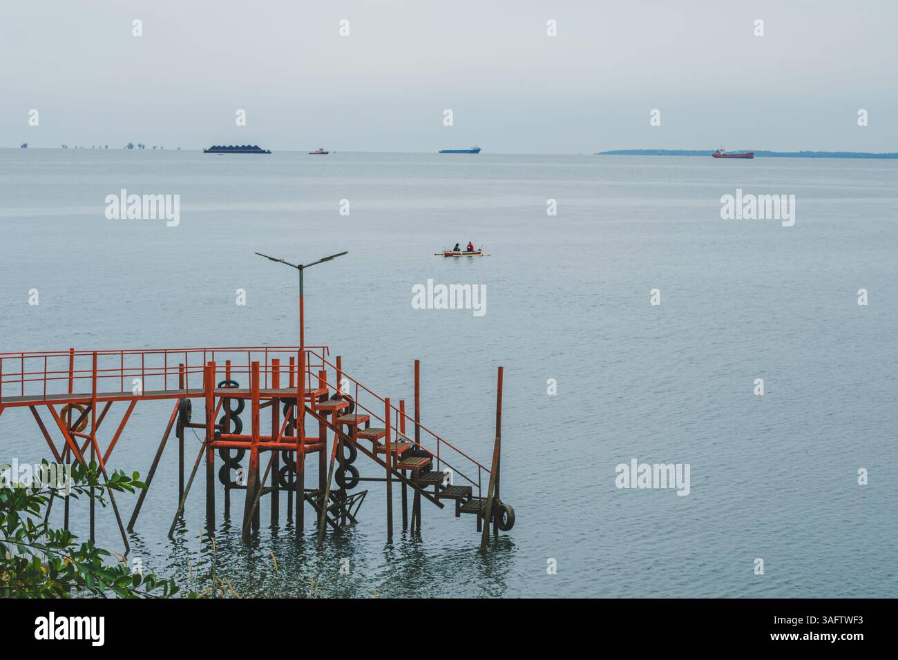 A peaceful coastal scene with a distinctive red pier leading out into ...