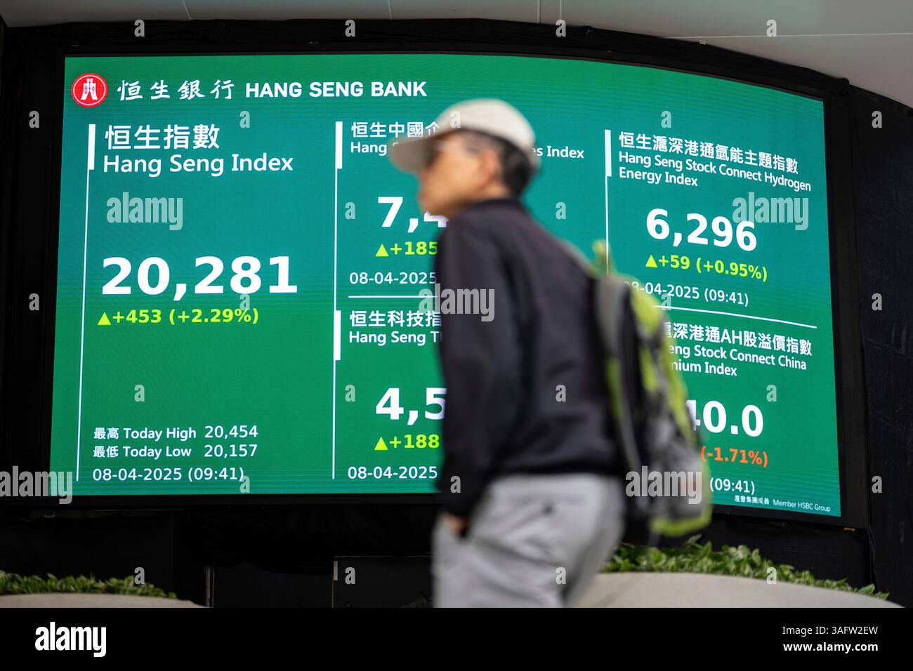 A pedestrians walks past an electronic screen displaying the Hang Seng ...