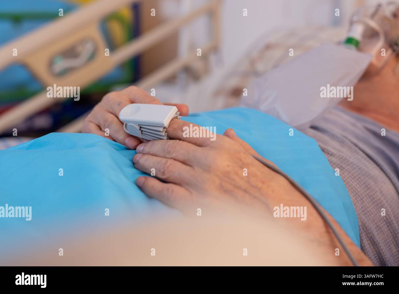 Elderly patient in hospital bed with pulse oximeter on finger and ...