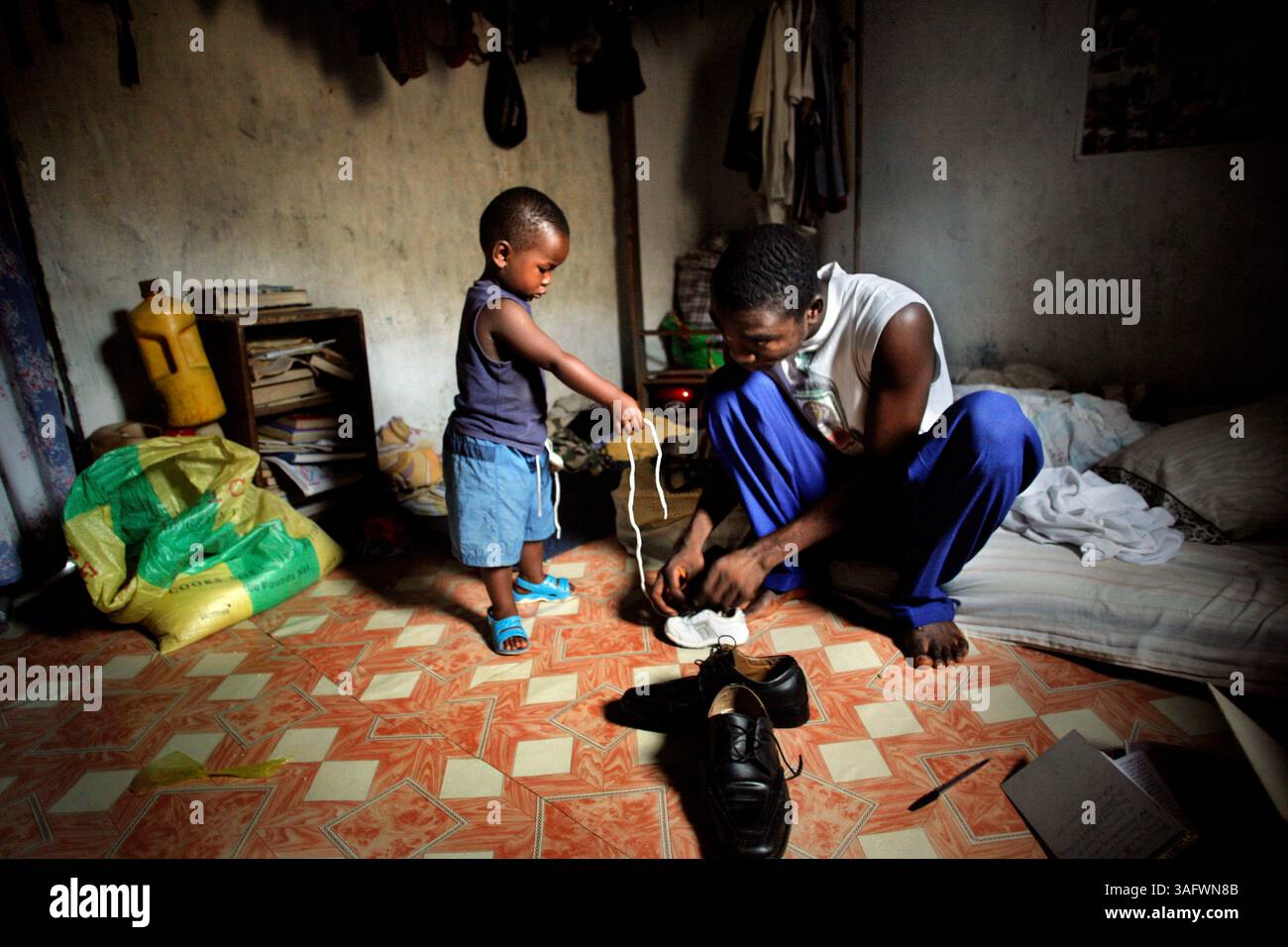 Liberia 3/2007) Moses Flomo, 2, hands his father William Flomo a shoe ...