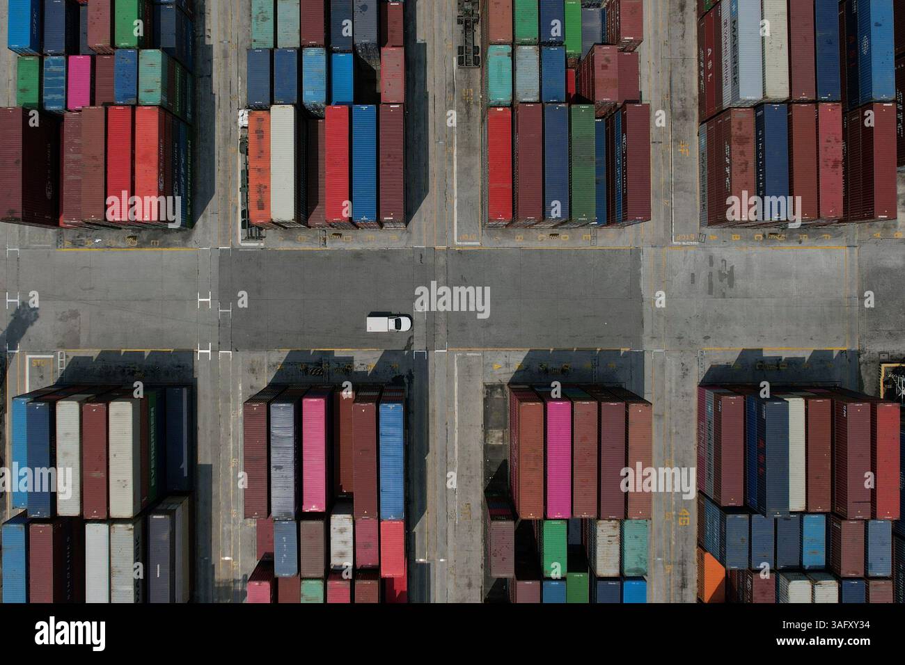 A vehicle drives along stacks of containers at the Manila International ...