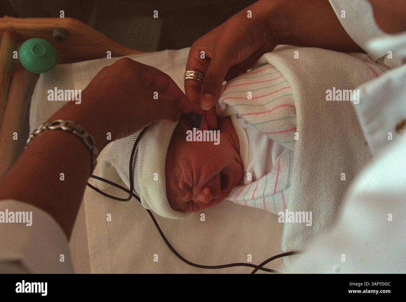 Rosibel Ortiz places a small probe tip in newborn Natalie Lisle's ear ...