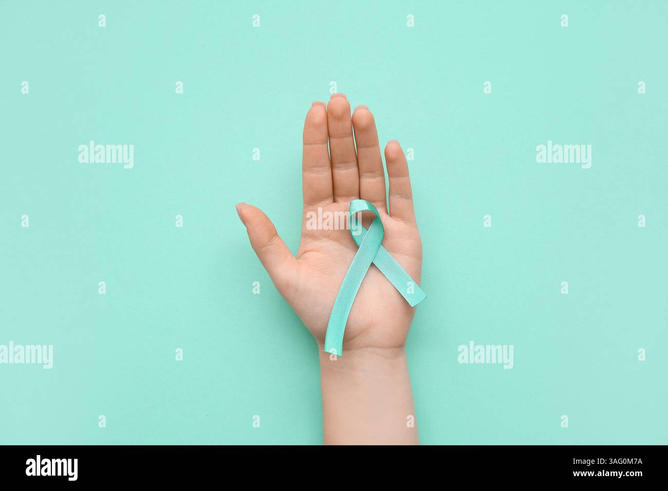 Female hand with turquoise ribbon on color background. Cervical Health ...