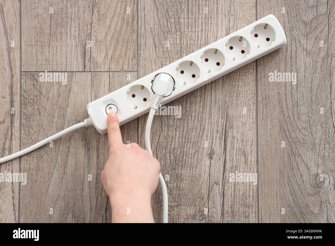 Female hand turning off extension cord on floor, top view. Unplug ...