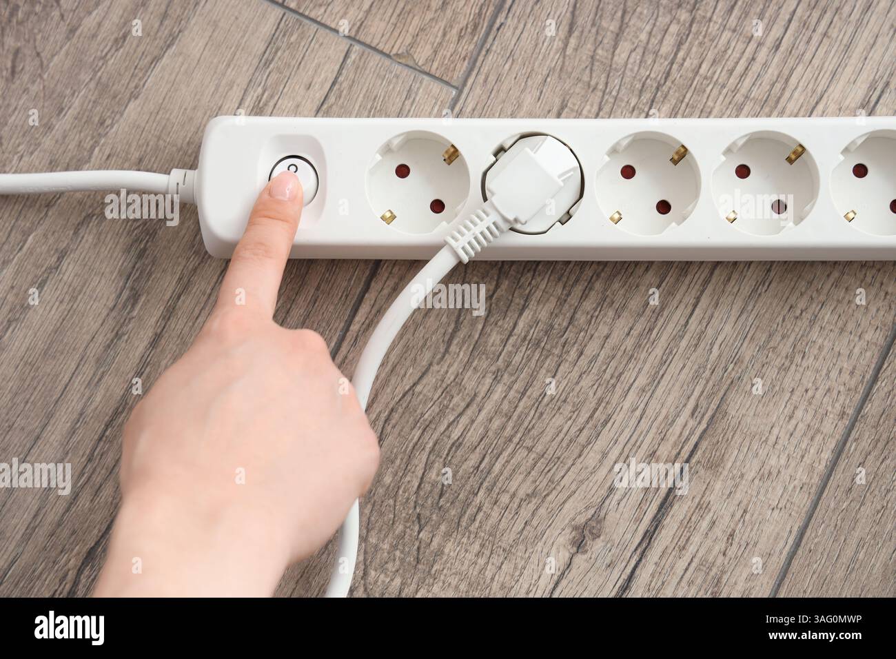 Female hand turning off extension cord on floor, top view. Unplug ...
