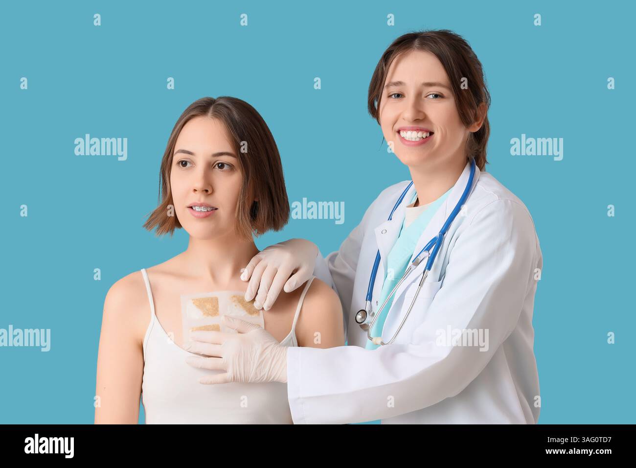 Female doctor applying mustard plaster on patient's chest against blue ...