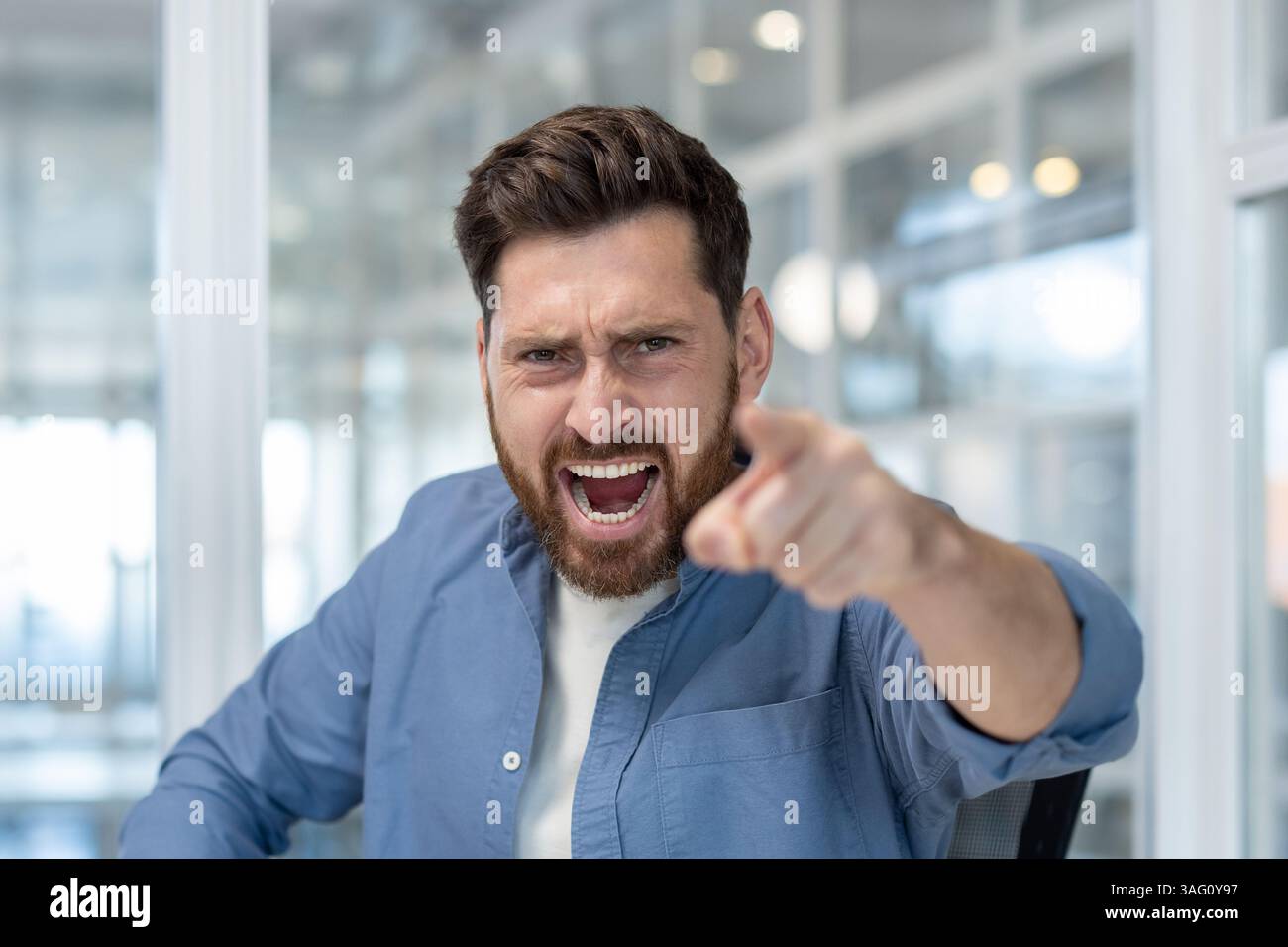 An angry man in a blue shirt points directly at the viewer, yelling ...