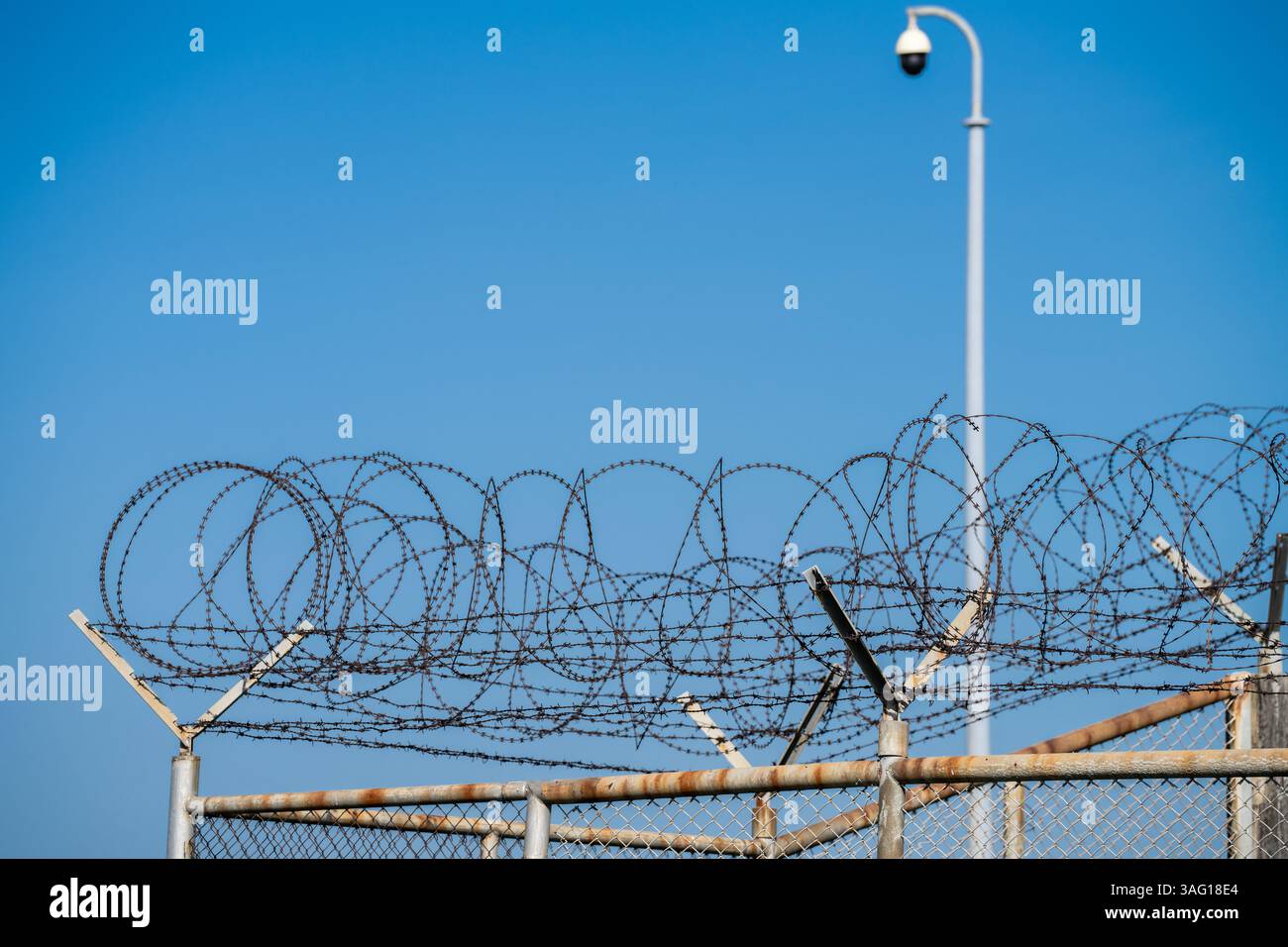 Barbed wire fence with CCTV. Border control and restricted migration. Political tension ...