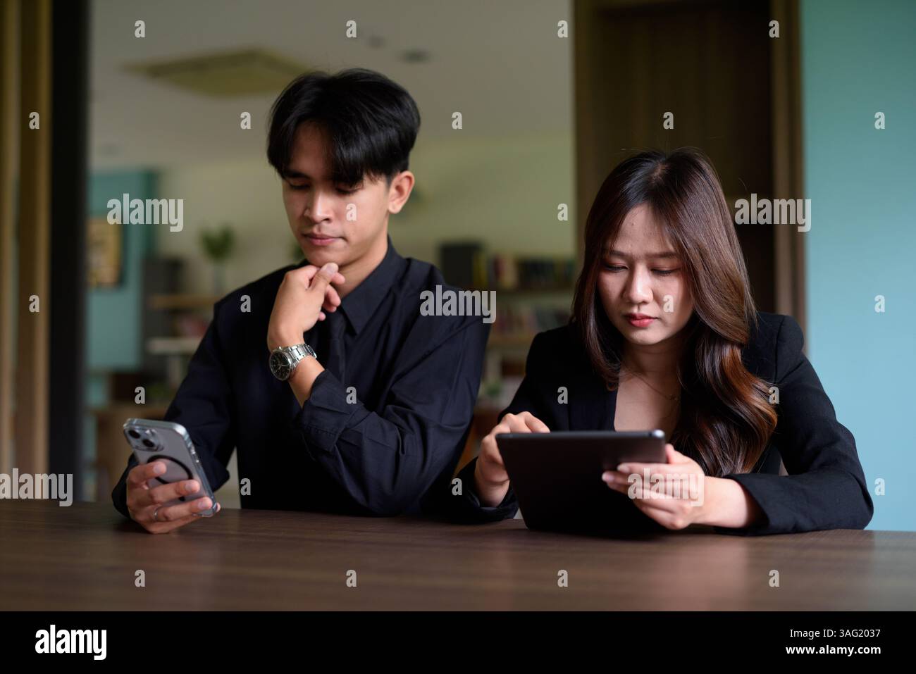 Young Asian couple sitting together in library in business uniform Stock Photo - Alamy