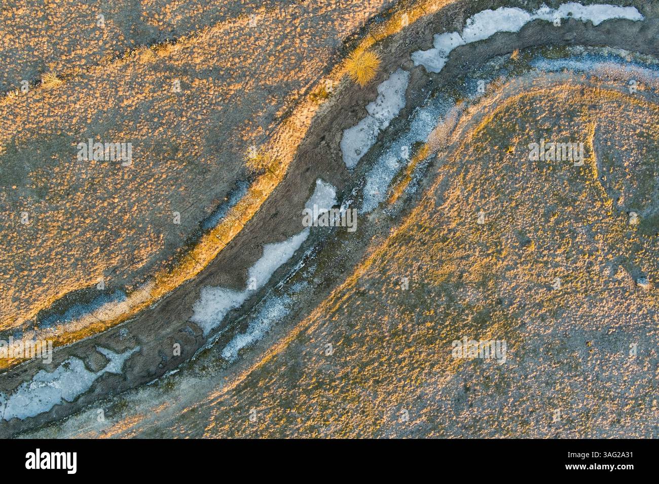 Aerial view of a winding dry riverbed meandering through dry meadows ...