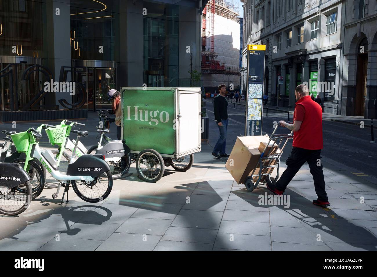 A delivery man pushes a trolley past Lime e-Bikes which stand beneath ...