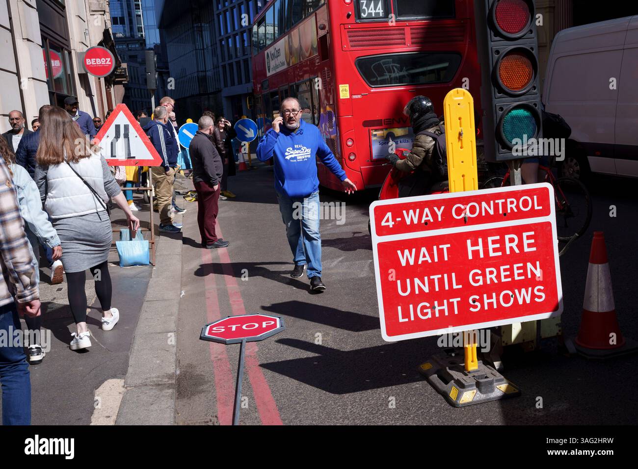 City workers and other pedestrians pass roadworks signs on Bishopsgate ...