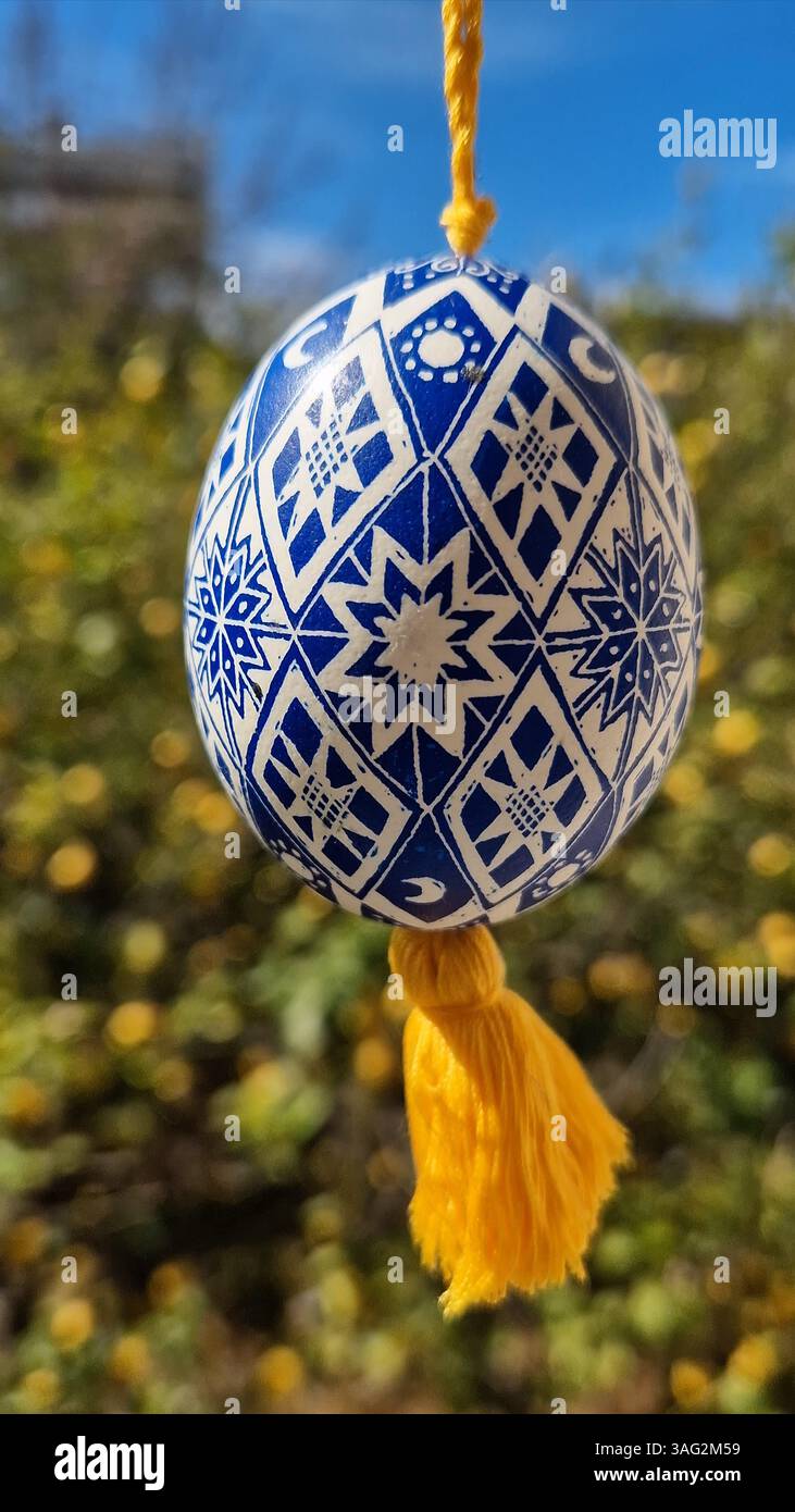 A stunning Ukrainian pysanka hangs with a yellow tassel, showcasing ...