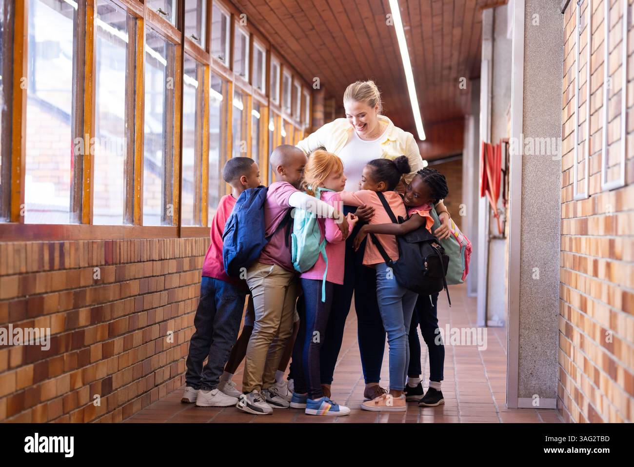 Female teacher hugging group of school diverse children with backpacks ...