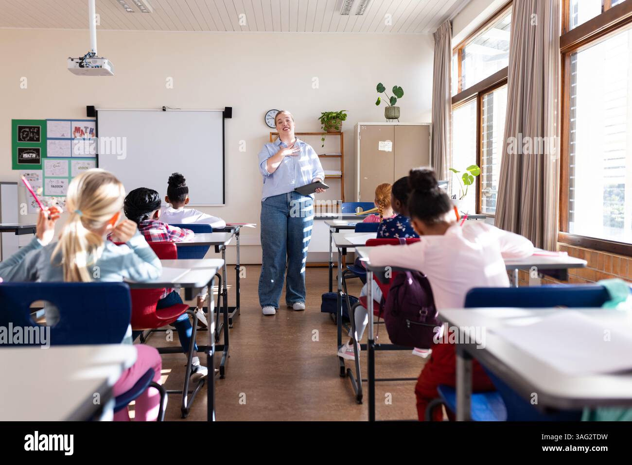 In school, female teacher instructing diverse group of students in ...