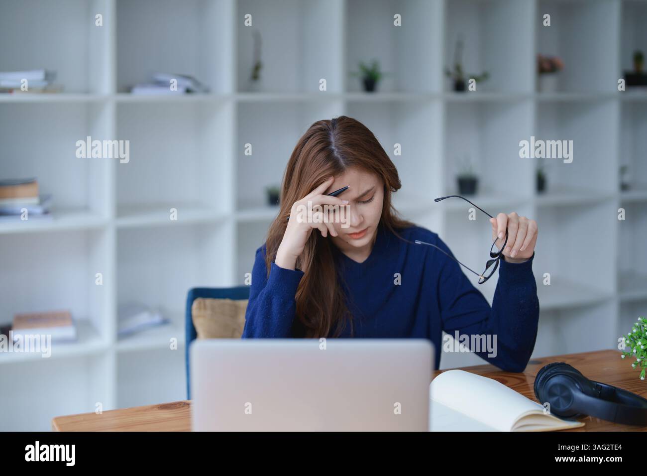 Stressed young woman overwhelmed by e-learning studies at desk with ...