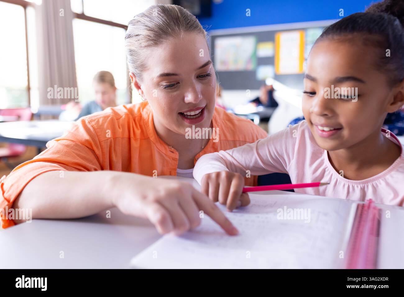 At school, Female teacher helping girl with homework in classroom ...