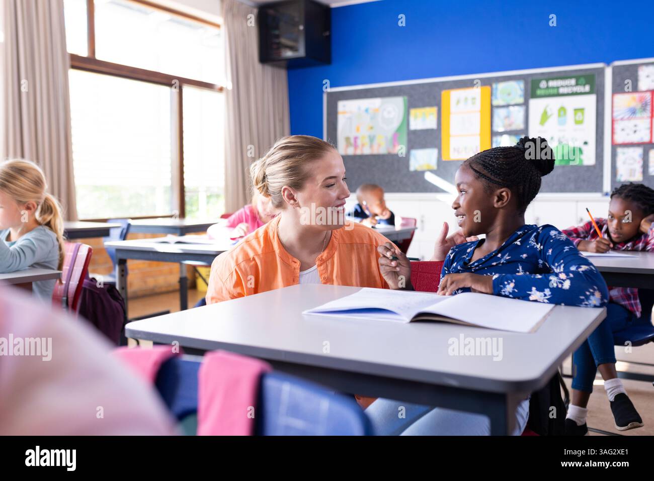 In school, female teacher helping african american girl with classwork ...