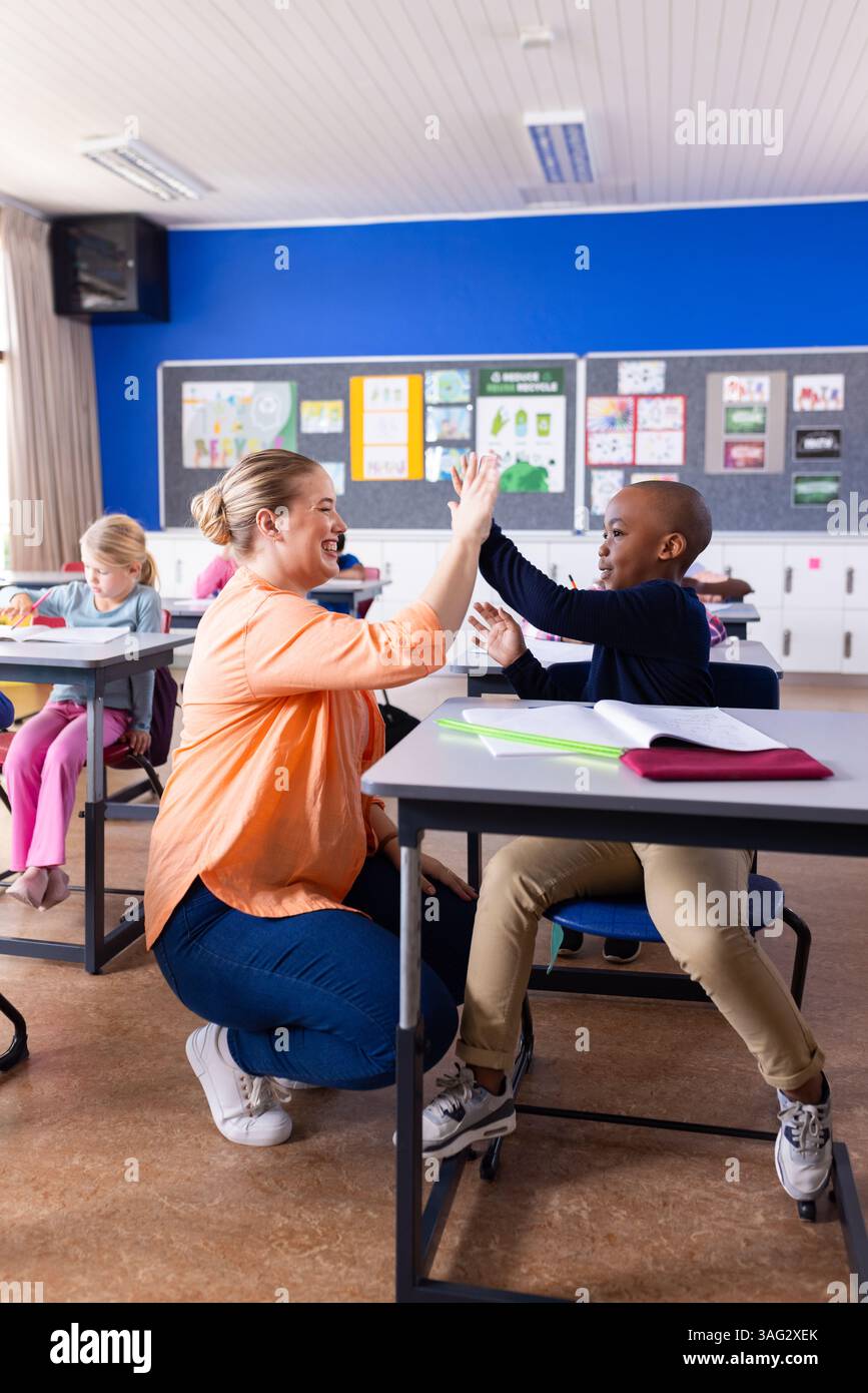High-fiving african american boy in classroom, female teacher ...