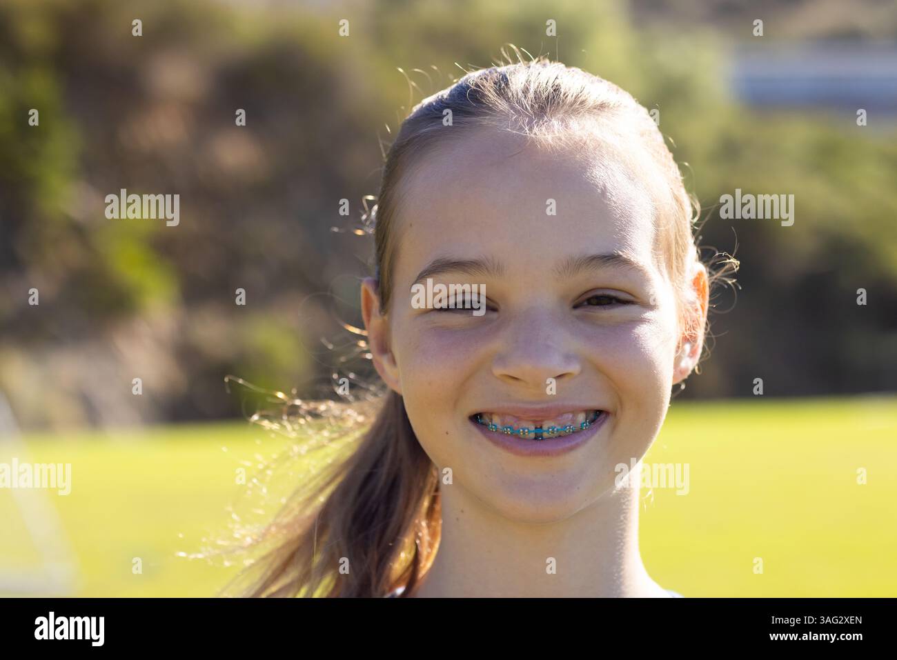 Smiling girl with braces enjoying outdoor time at school playground ...