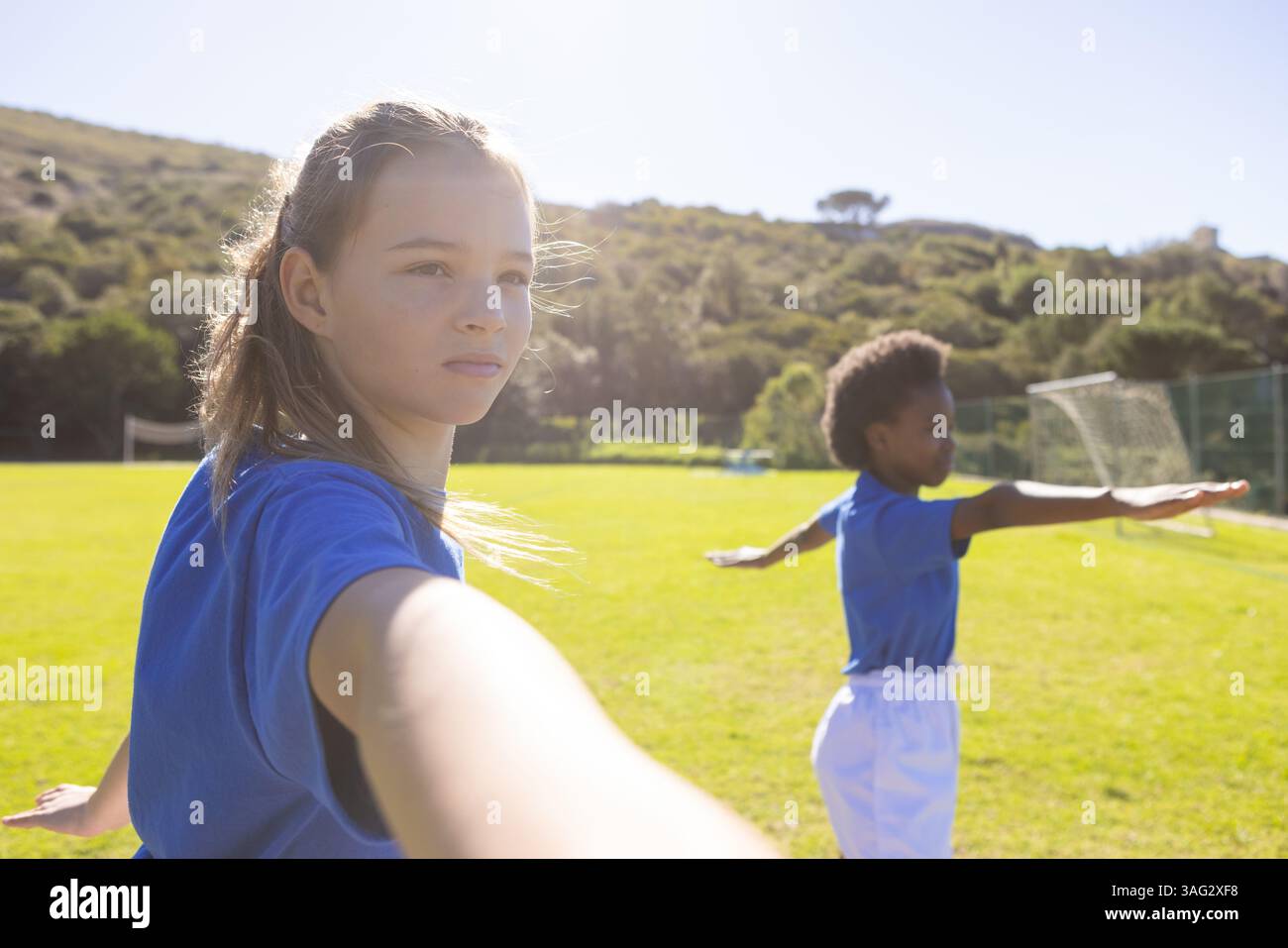 Practicing stretching exercises, diverse girls in school enjoying ...