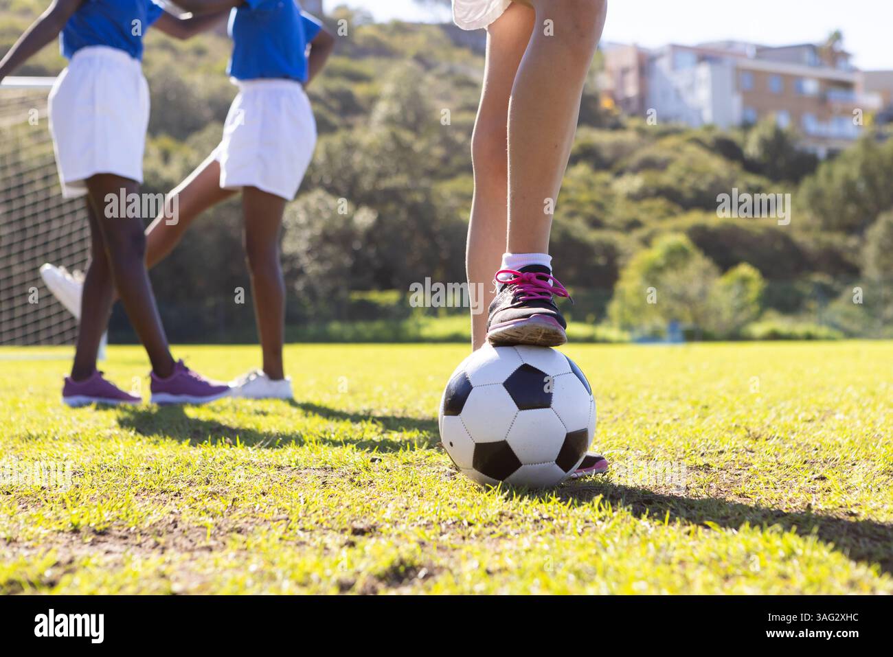 Playing soccer on school field, diverse girls in sports uniforms ...