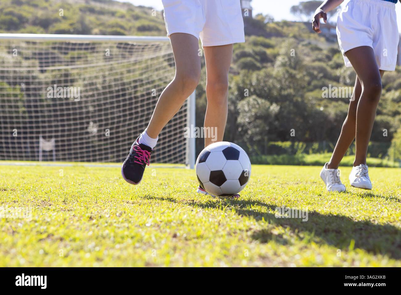 Playing soccer on field, diverse girls in school uniforms enjoying ...