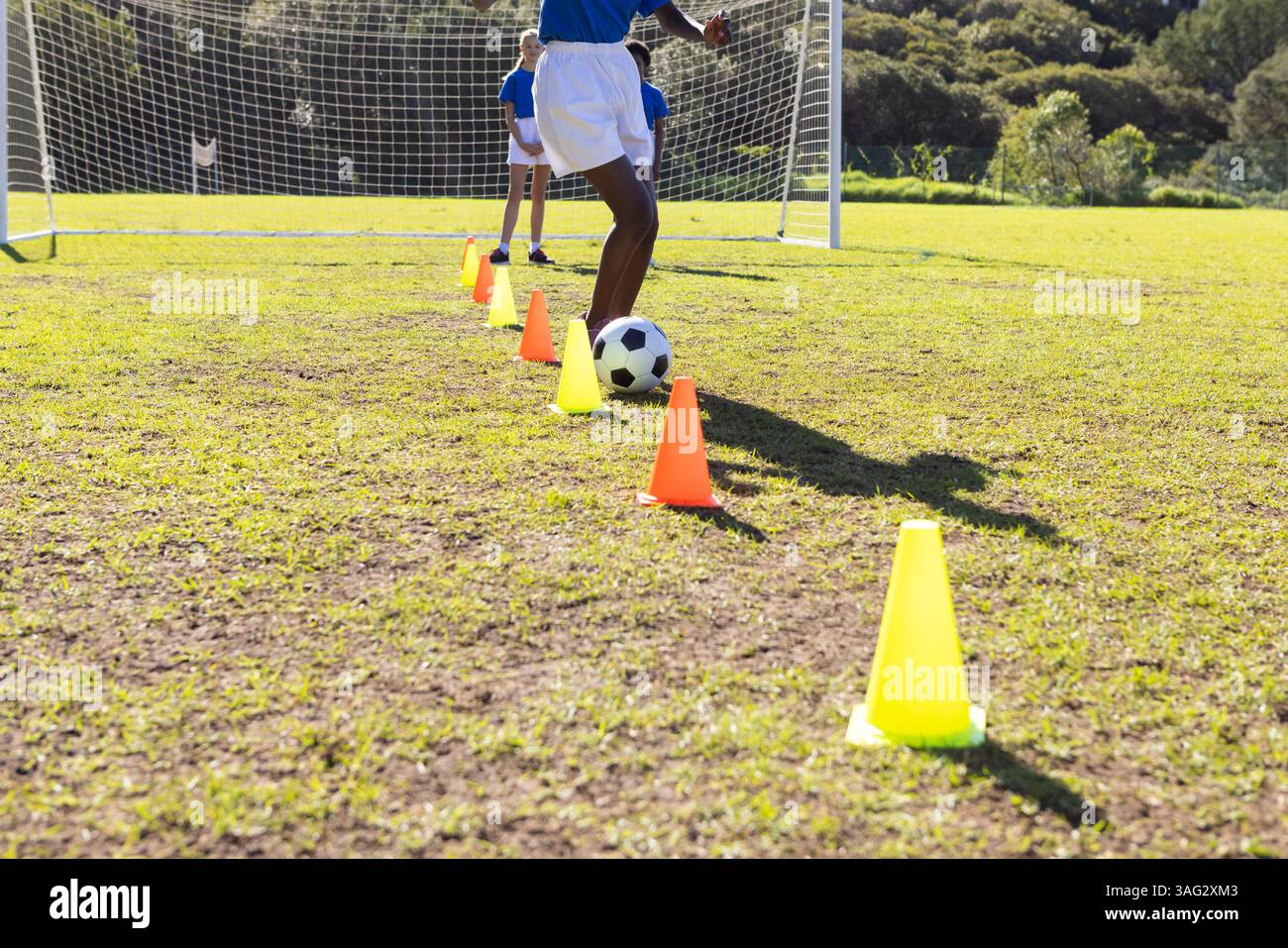 Dribbling soccer ball through cones, diverse girls practicing soccer ...