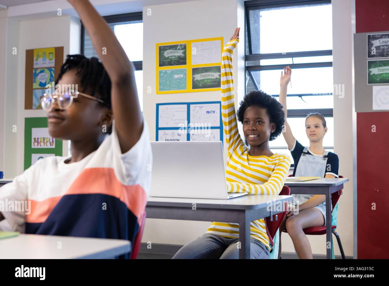 In school, diverse students raising hands in classroom, participating ...