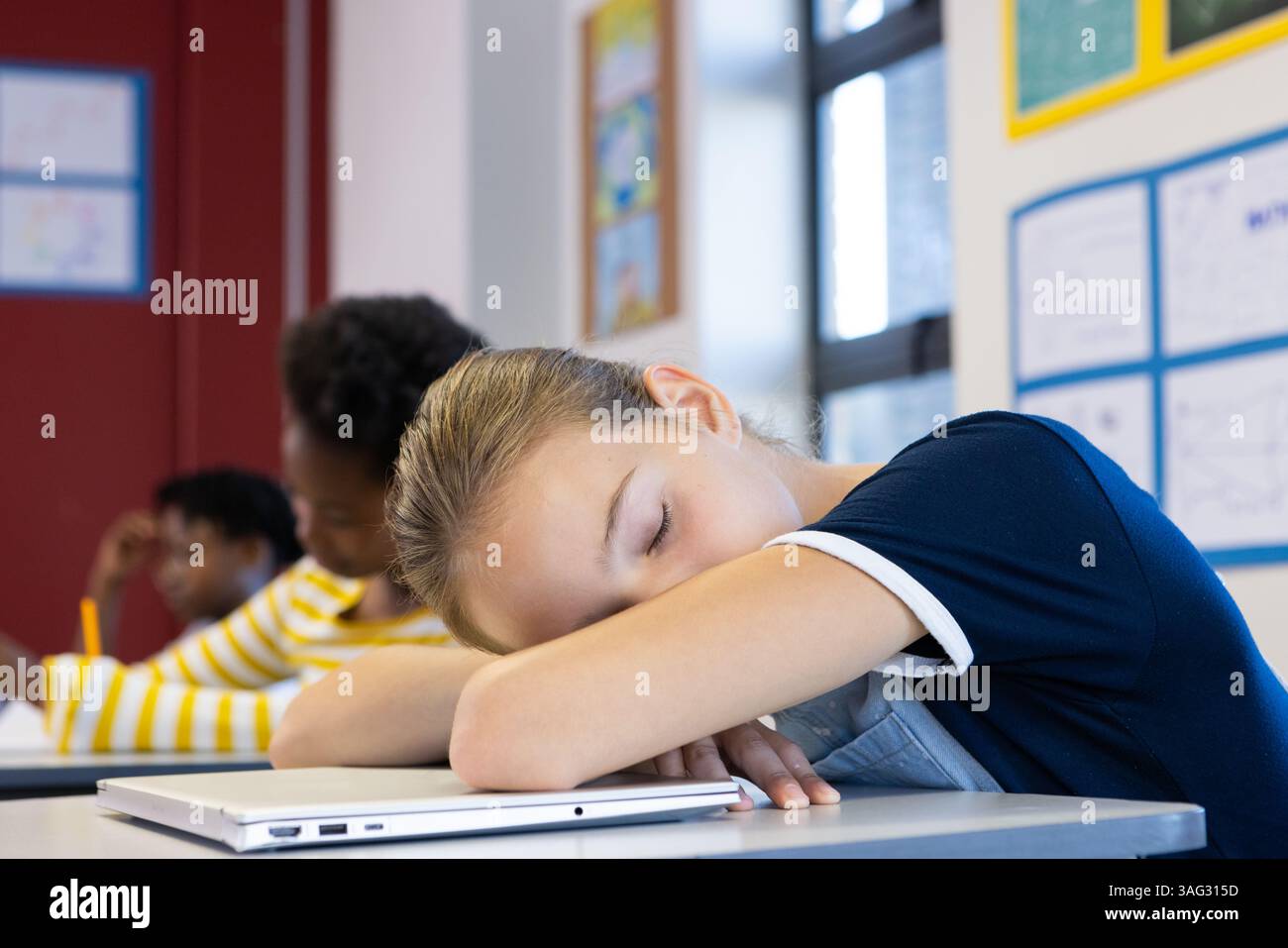 Sleeping on desk with laptop, girl in school classroom during lesson ...