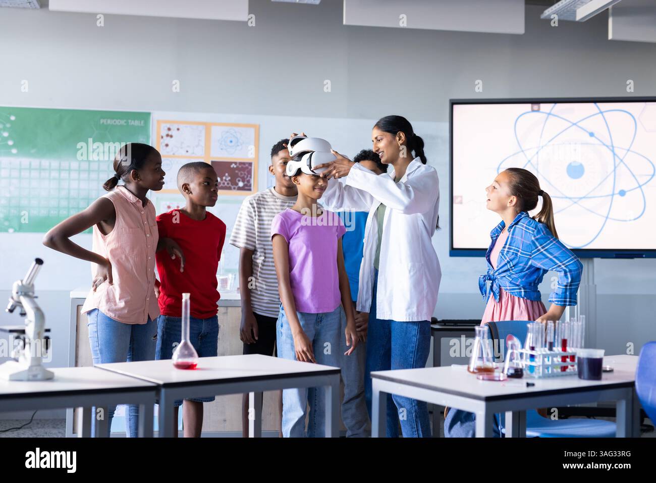 In school, Indian female teacher helping students use VR headset in ...