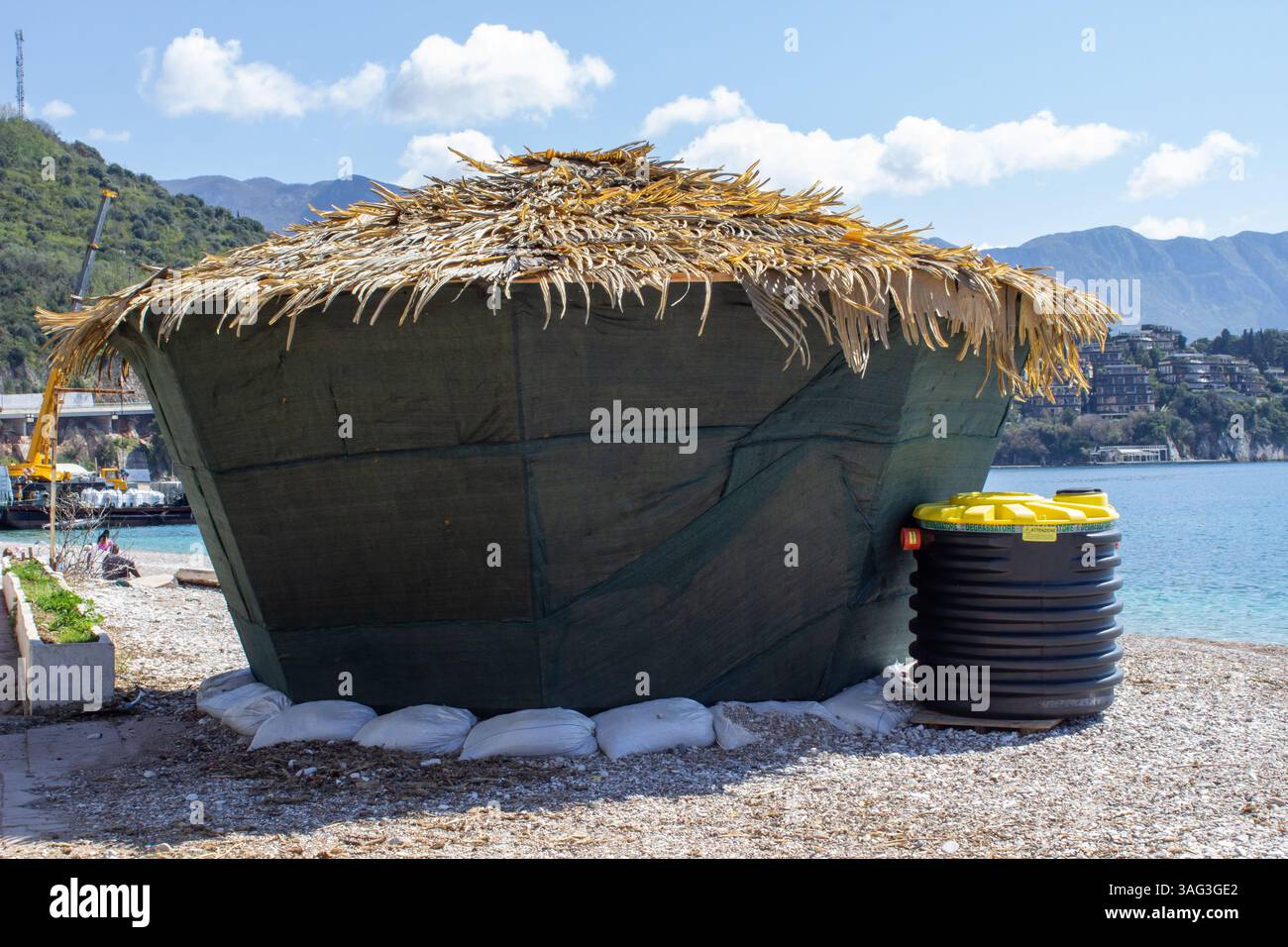 A building with a thatched roof on the seashore near a garbage bin ...