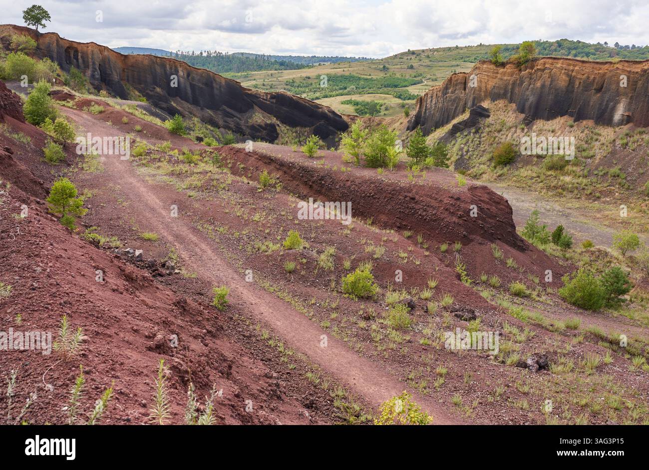 Eroded red volcanic terrain with hiking trail through rugged cliffs and ...