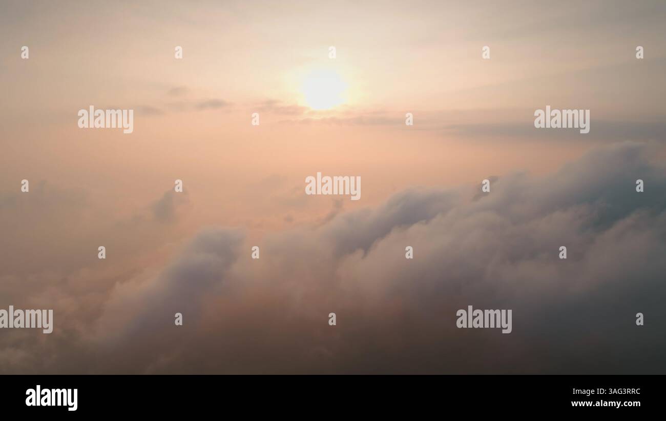 Warm sunlight shining through clouds during beautiful sunset, aerial drone view flying above ...