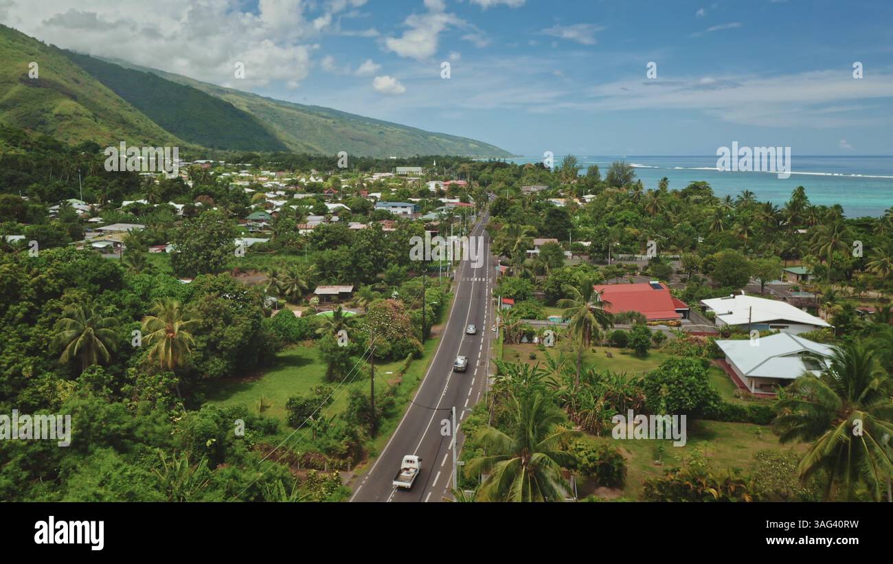 Lush tropical vegetation enveloping houses and a winding road leads to ...