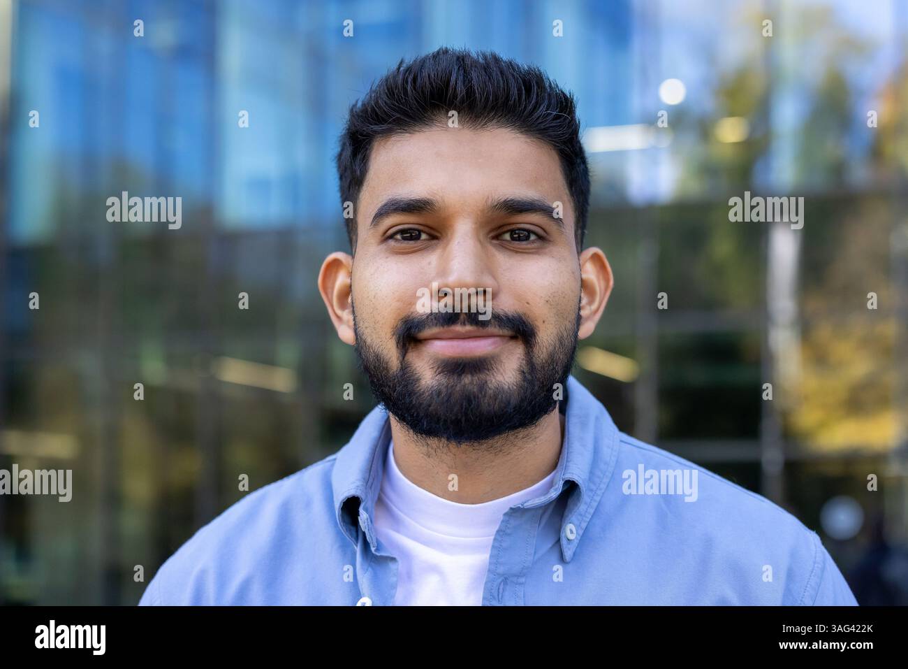 A handsome man with a beard smiles directly at the camera while ...