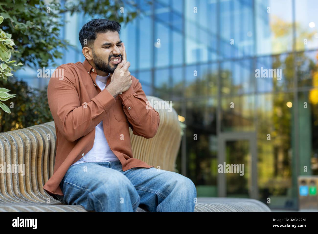 A man with a pained expression clutches his jaw, clearly suffering from ...