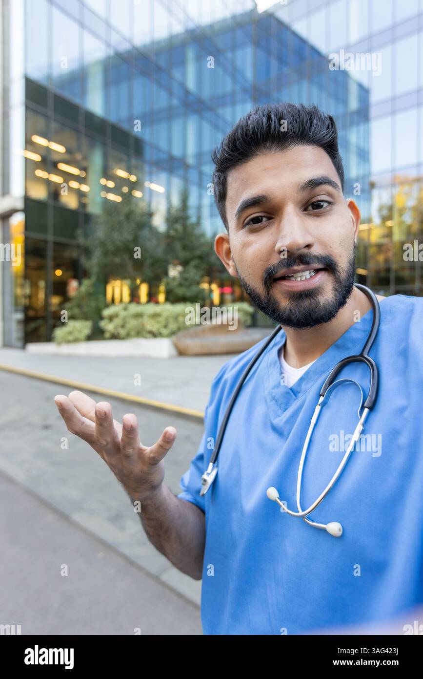 A friendly doctor gestures toward the camera while standing outside a ...