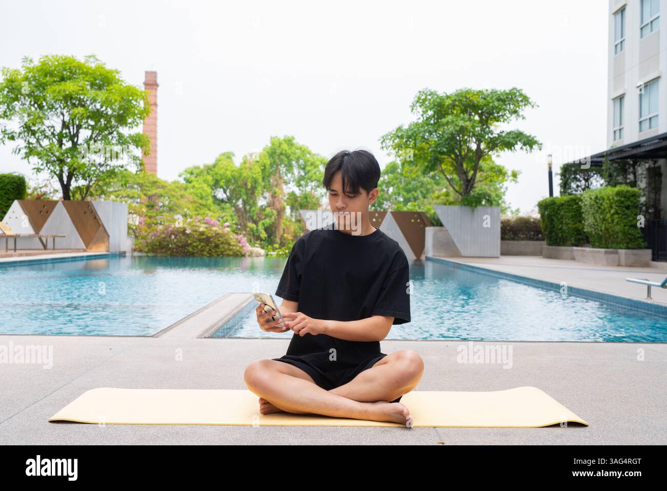 Young man doing yoga outdoors next to swimming pool during summer Stock ...