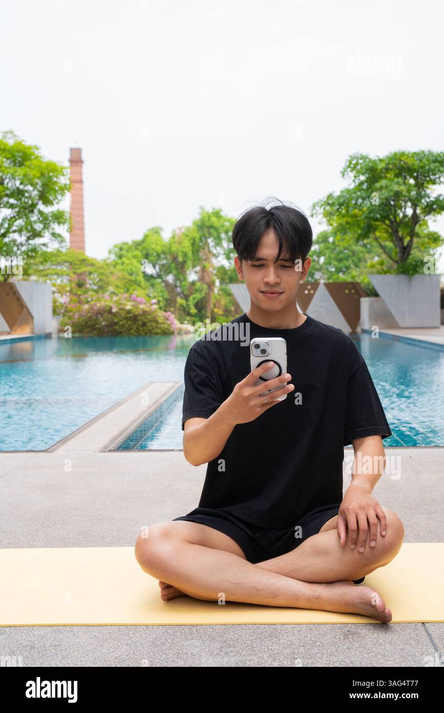Young man doing yoga outdoors next to swimming pool during summer Stock ...