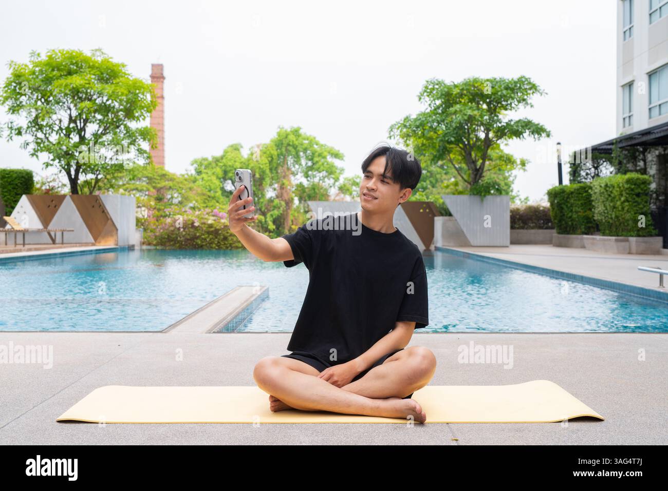 Young man doing yoga outdoors next to swimming pool during summer Stock ...