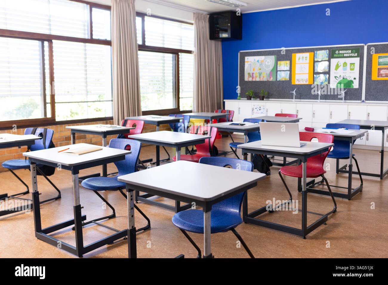 Empty classroom with desks and chairs, laptop on one desk, bright ...